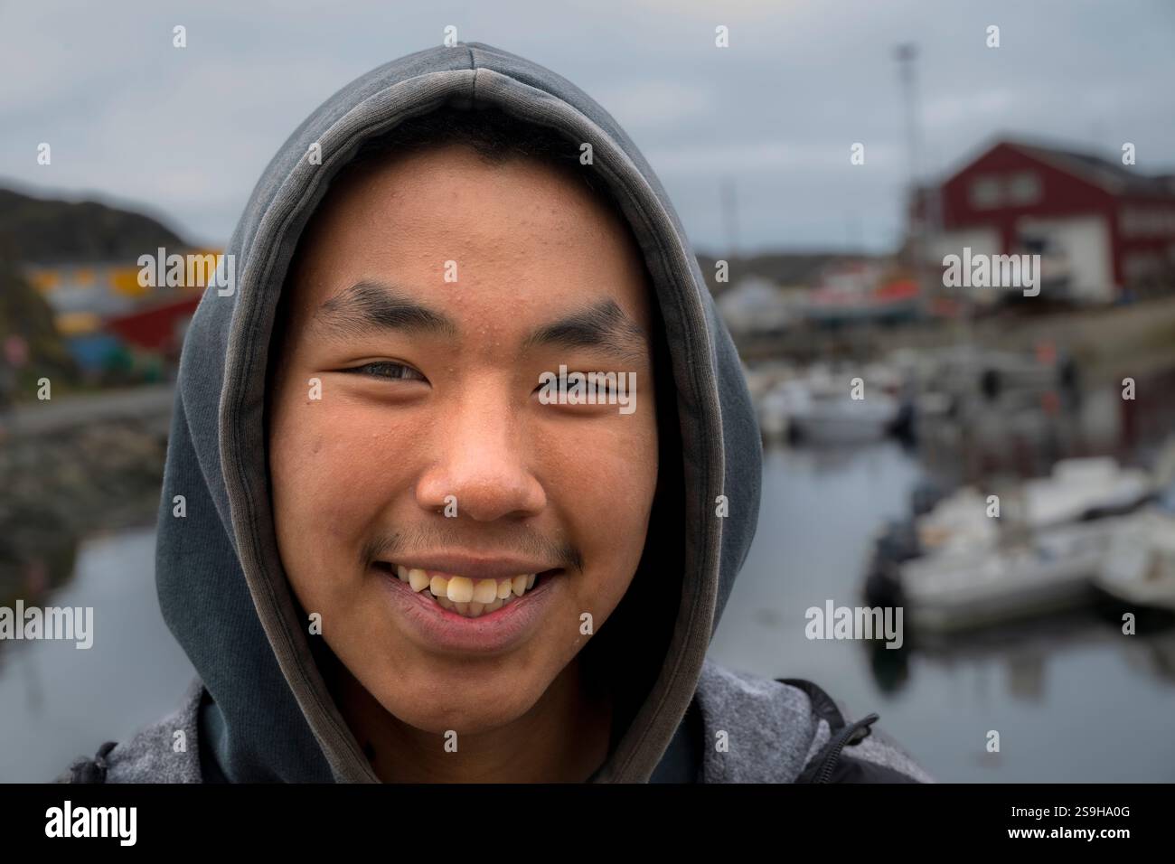 A young Inuit man poses near the harbor in Sisimiut, Greenland, with ...