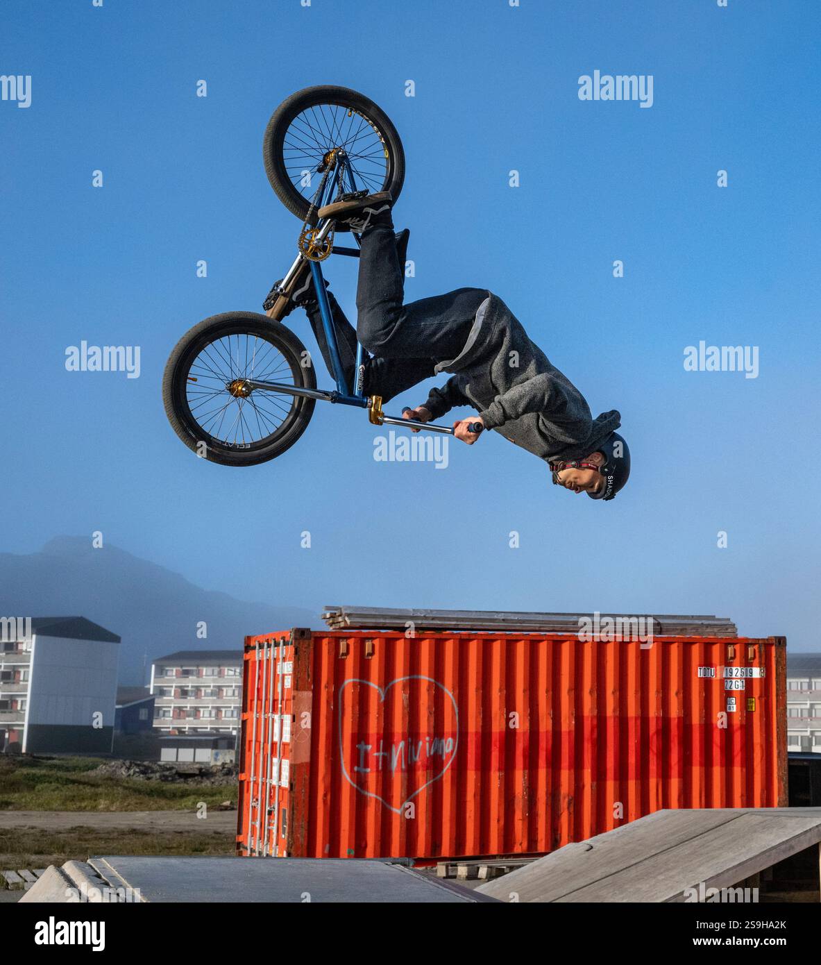A BMX rider showcases skill by flipping upside down over a shipping ...