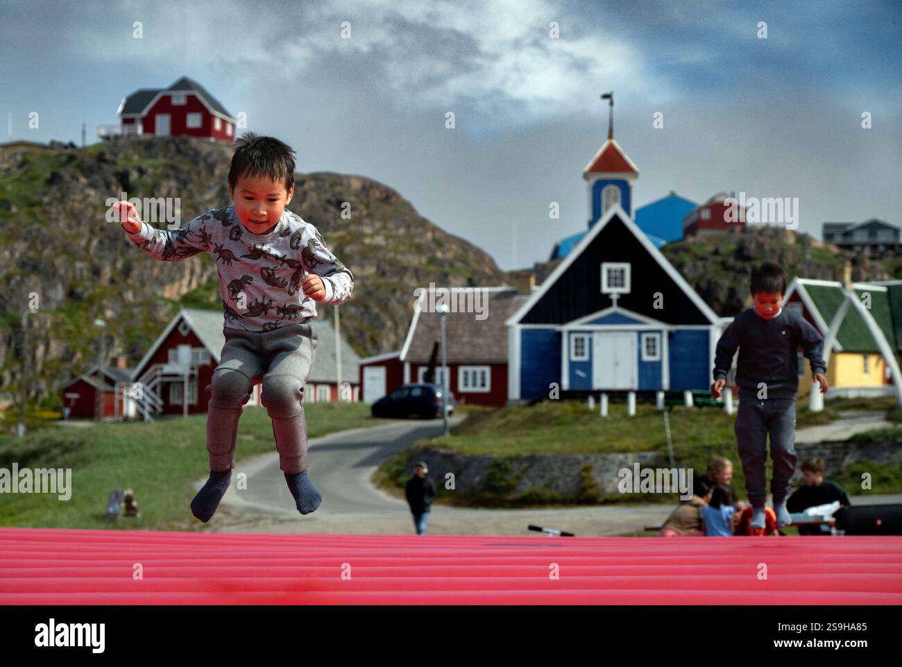 Inuit children are having fun jumping on a large inflatable surface in ...