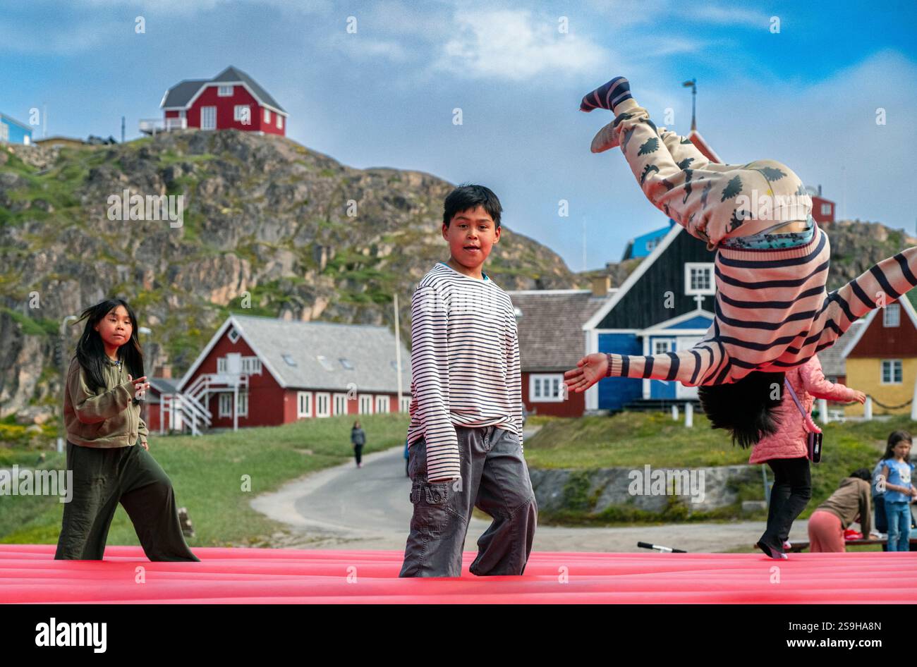 A lively group of children play and perform acrobatic tricks on a ...