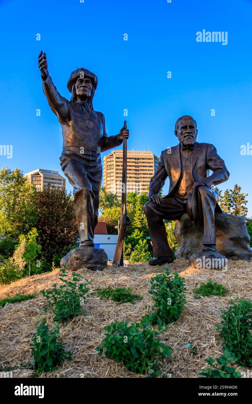 Two statues of men sitting on a rock, one of them holding a shovel. The ...