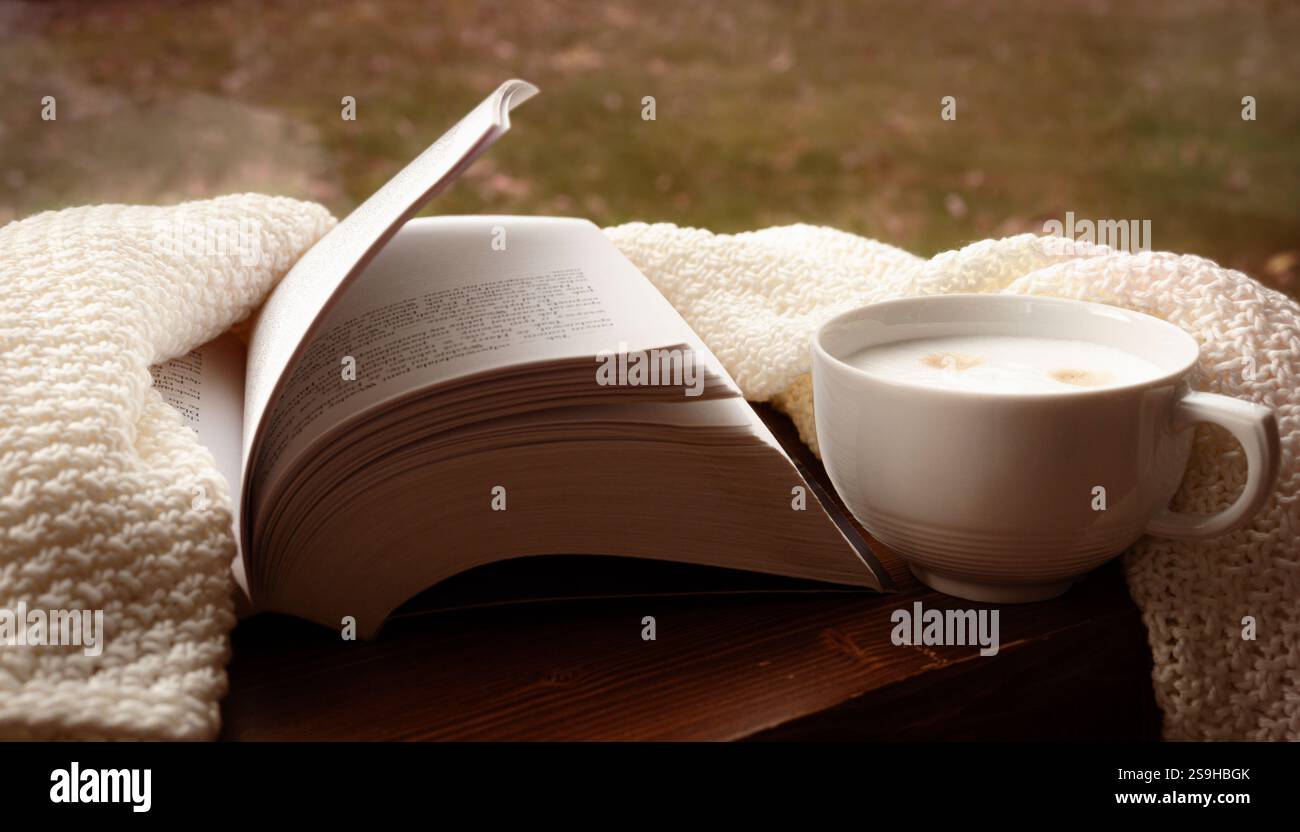 Warm cup of coffee, open book, beige soft warm blanket next to the ...