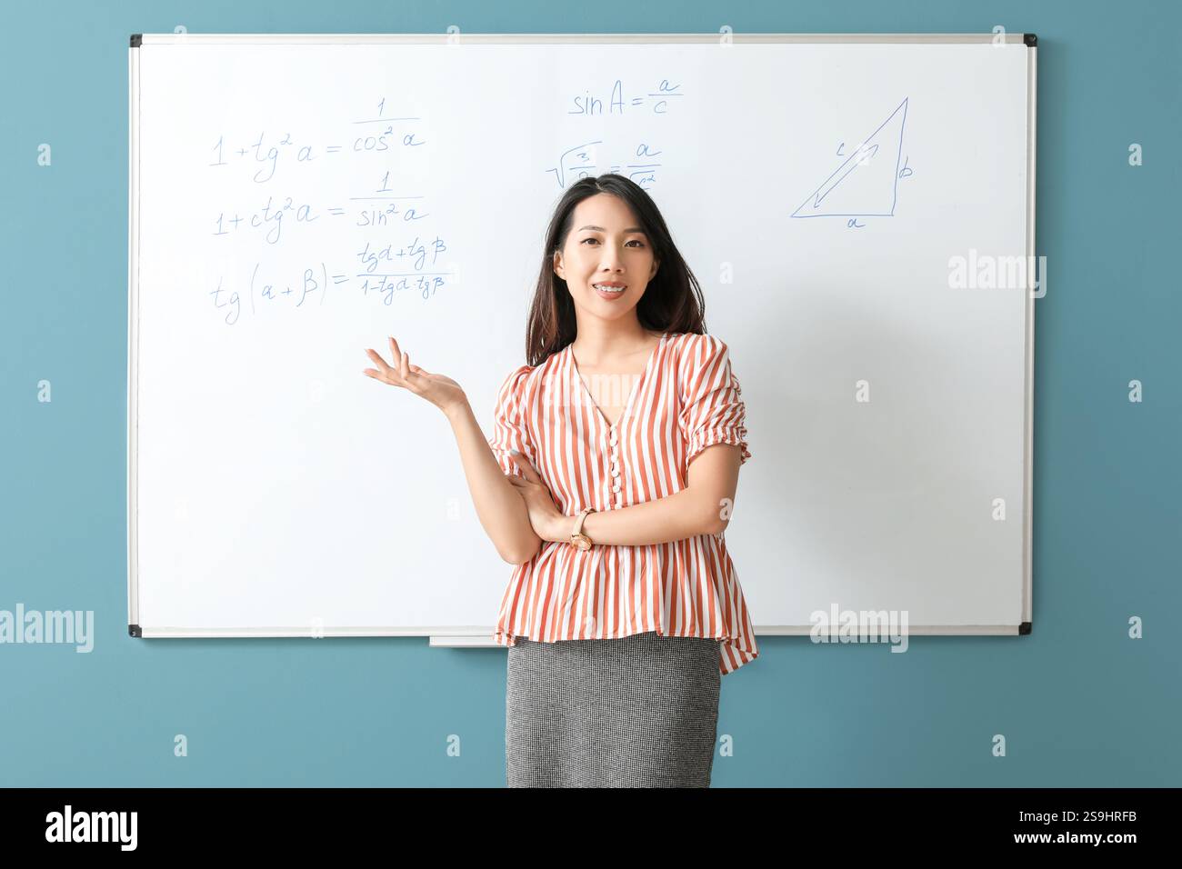 Asian Math teacher near flipboard in classroom Stock Photo - Alamy