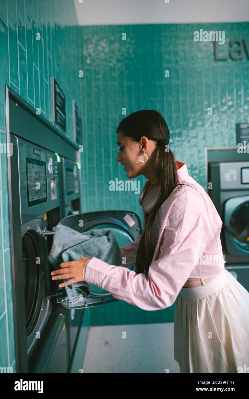A woman engaged in the process of doing laundry at a contemporary and modern laundromat facility ...