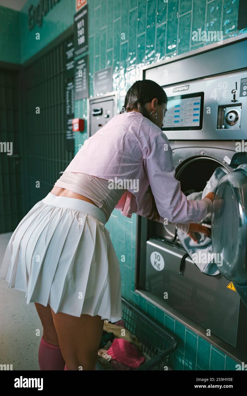 A young woman at a laundromat dressed in a stylish outfit while doing her laundry Stock Photo ...