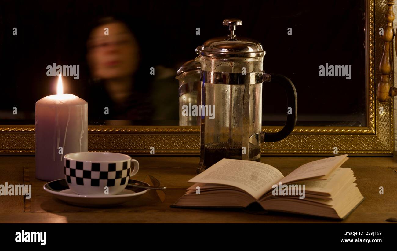 Ghost in the mirror. A cup of coffee, a book, french press, a candle ...