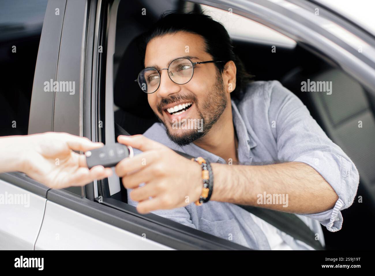 Handsome middle-eastern man taking car key from leasing service person ...