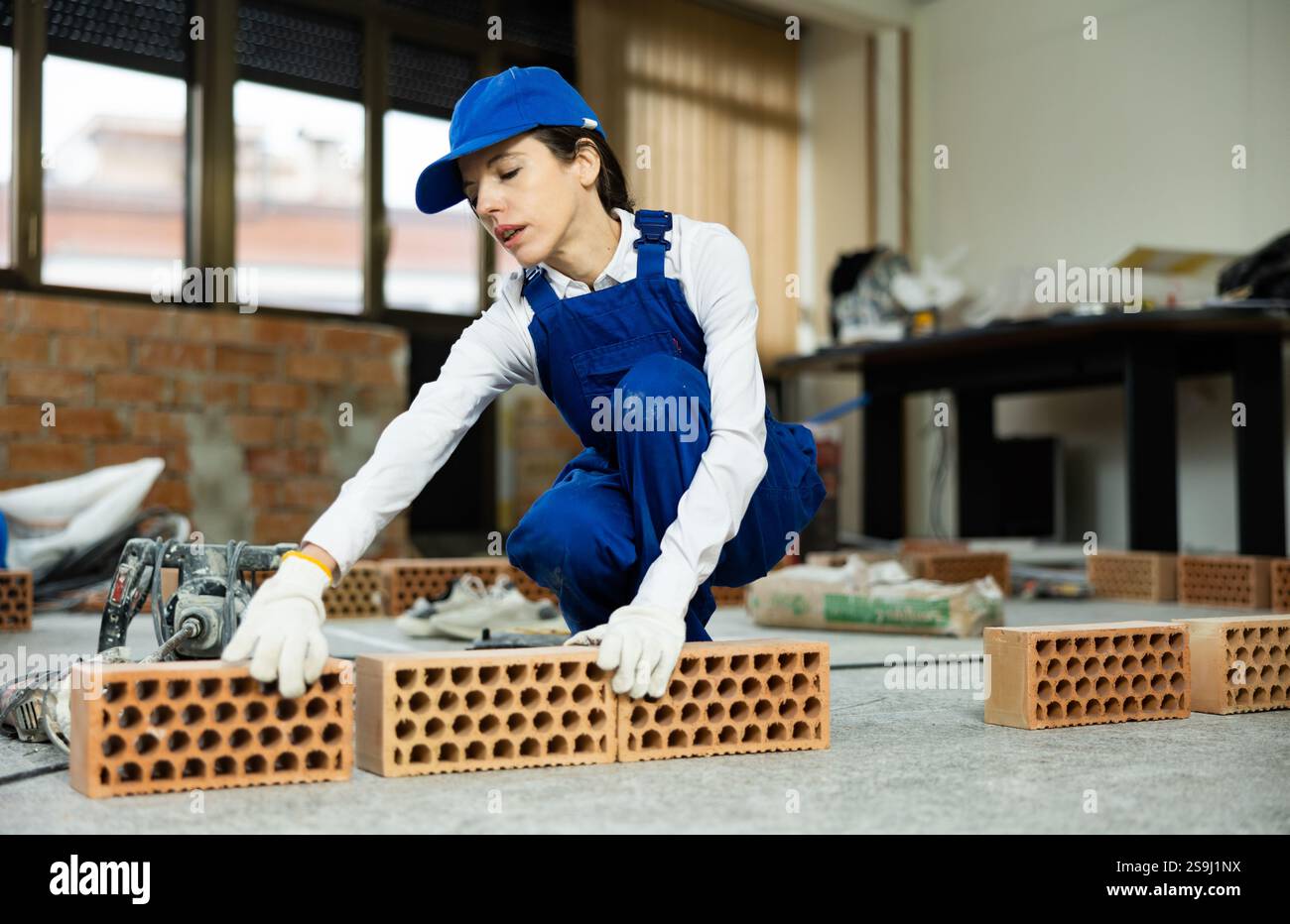 Workwoman preparing bricks for masonry at construction site indoors ...
