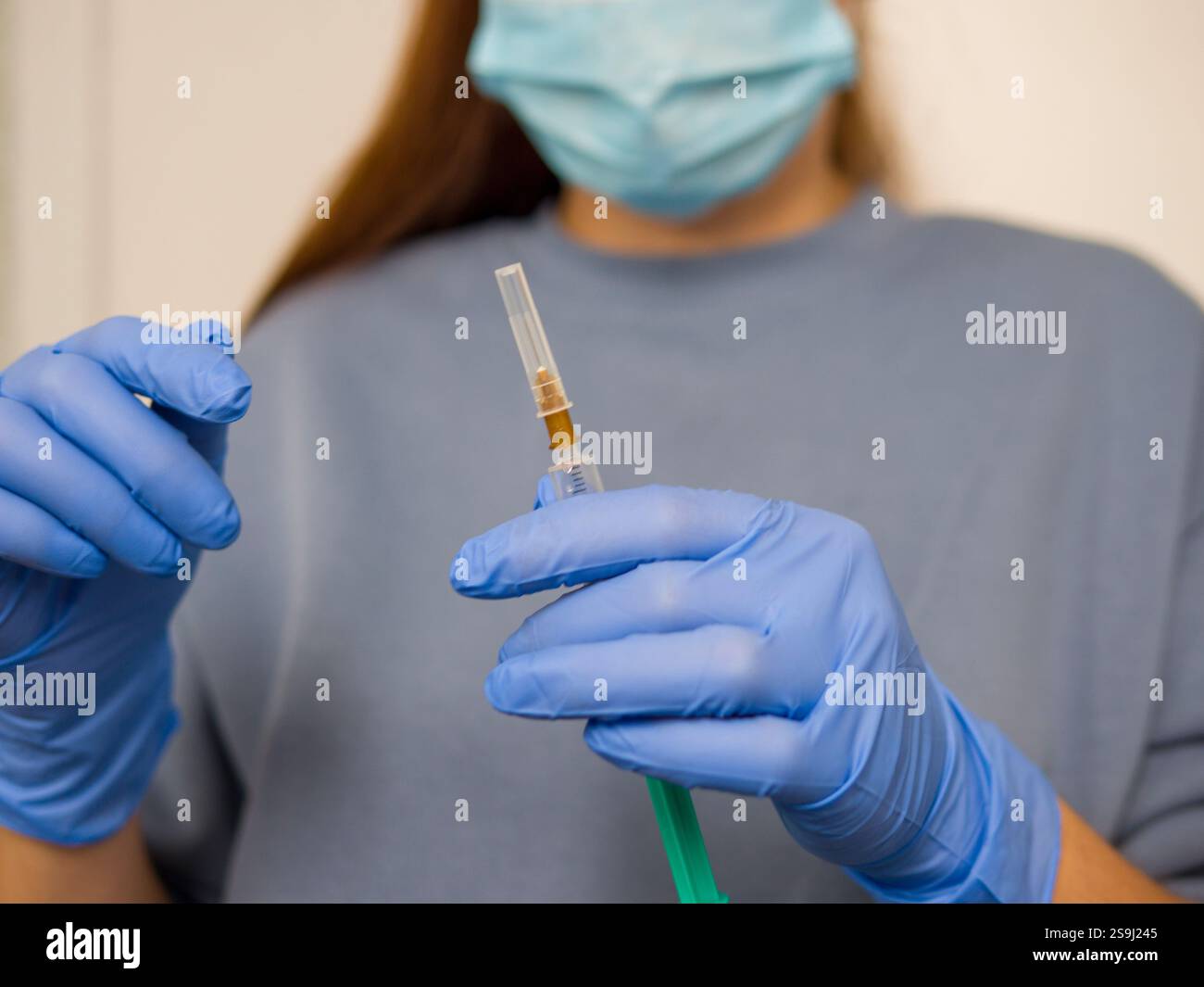 Doctor wearing a blue surgical mask and gloves, preparing a medicine ...
