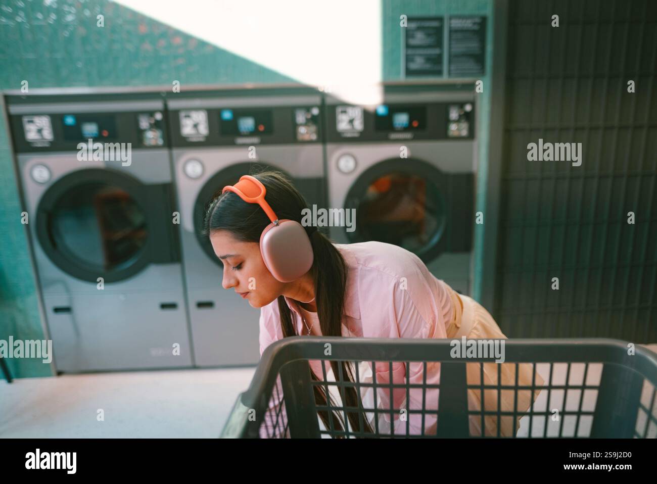 A Young Woman Enjoying Music in Laundry Room While Wearing Headphones ...