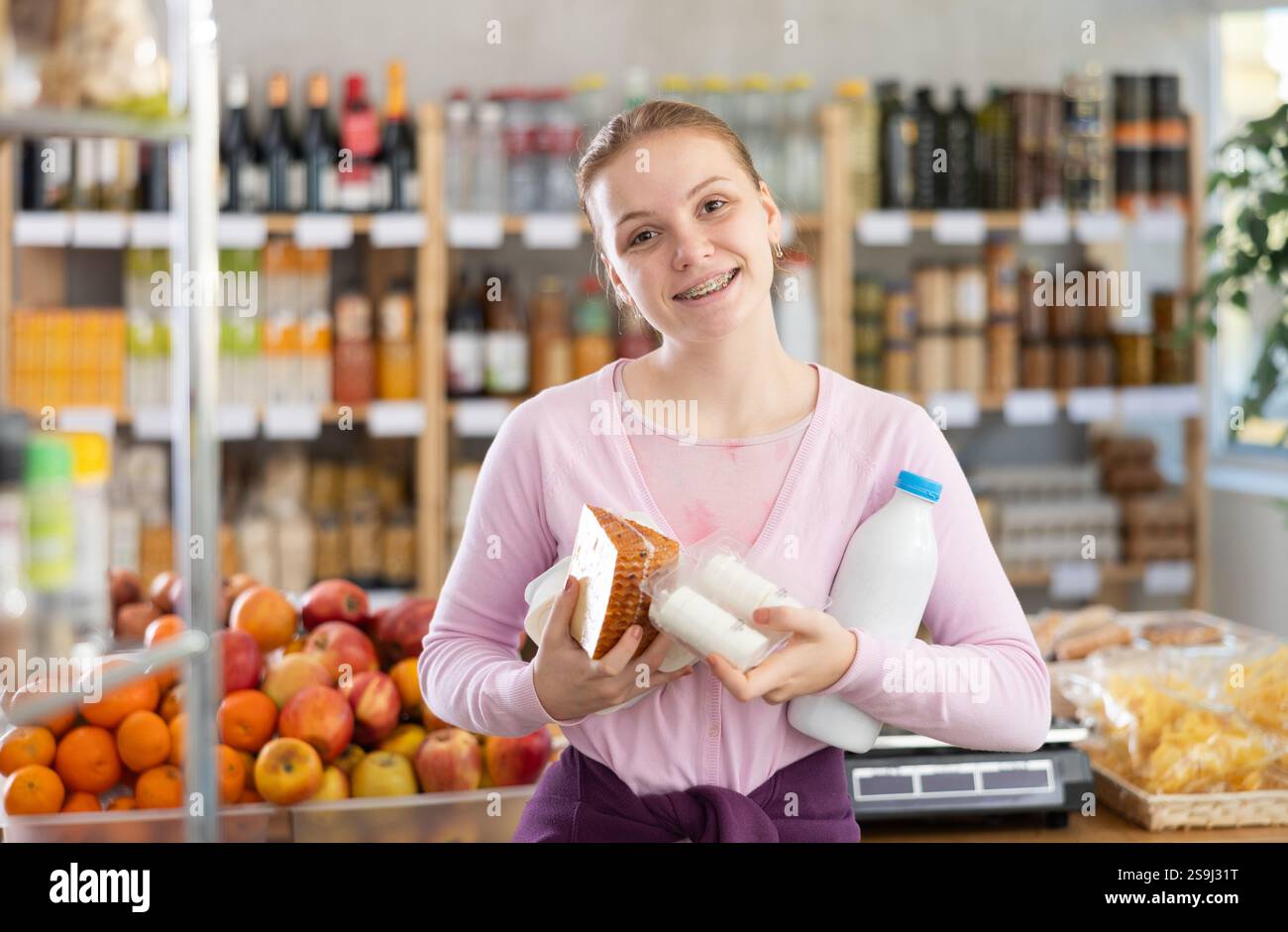 Female shopper with various dairy products in her hands continues to ...