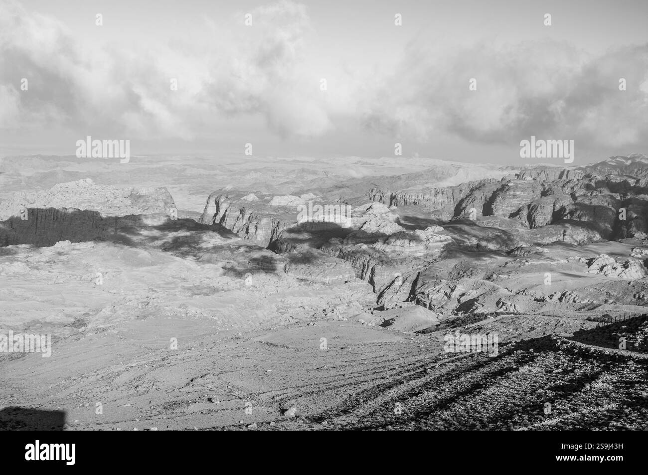 A desolate landscape with a few trees and a rocky hill. The sky is ...