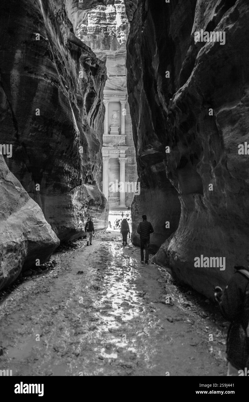 A group of people are walking down a narrow path in a cave. The cave is ...