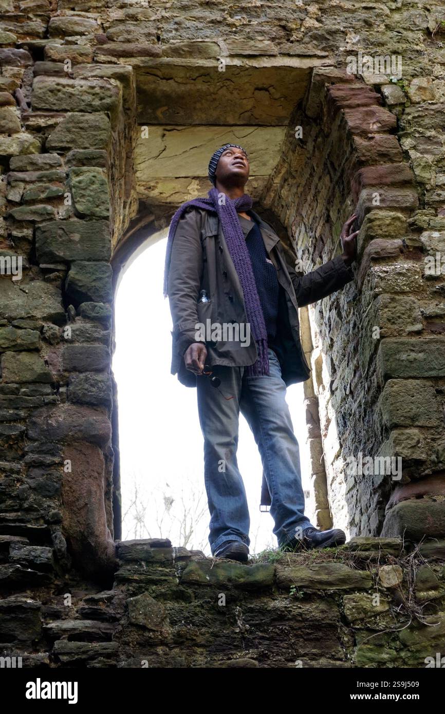 candid image of solitary young back man standing in alcove of ruined ...