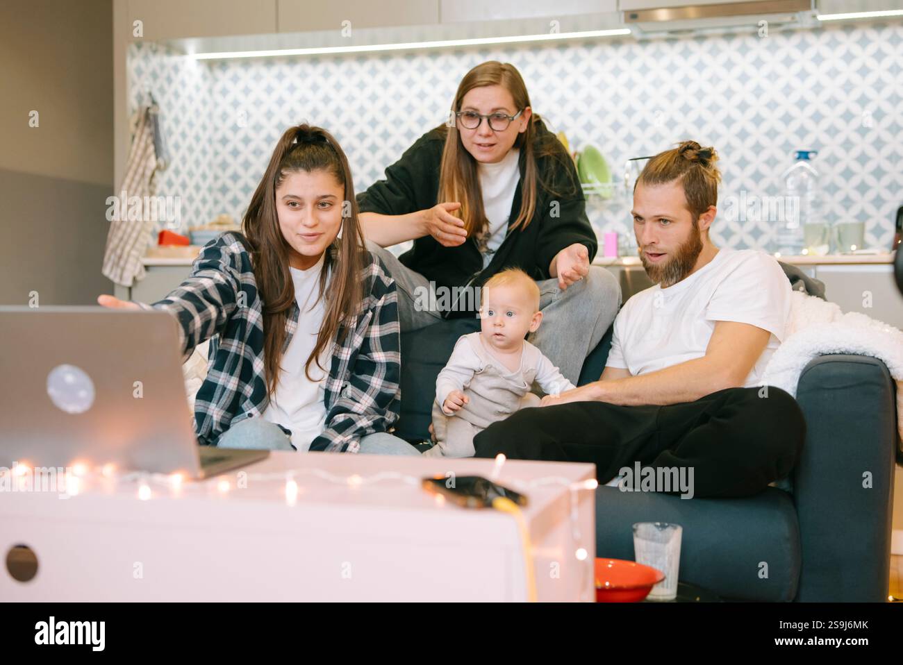 A family gathering occurs, where a baby engages with a laptop while ...