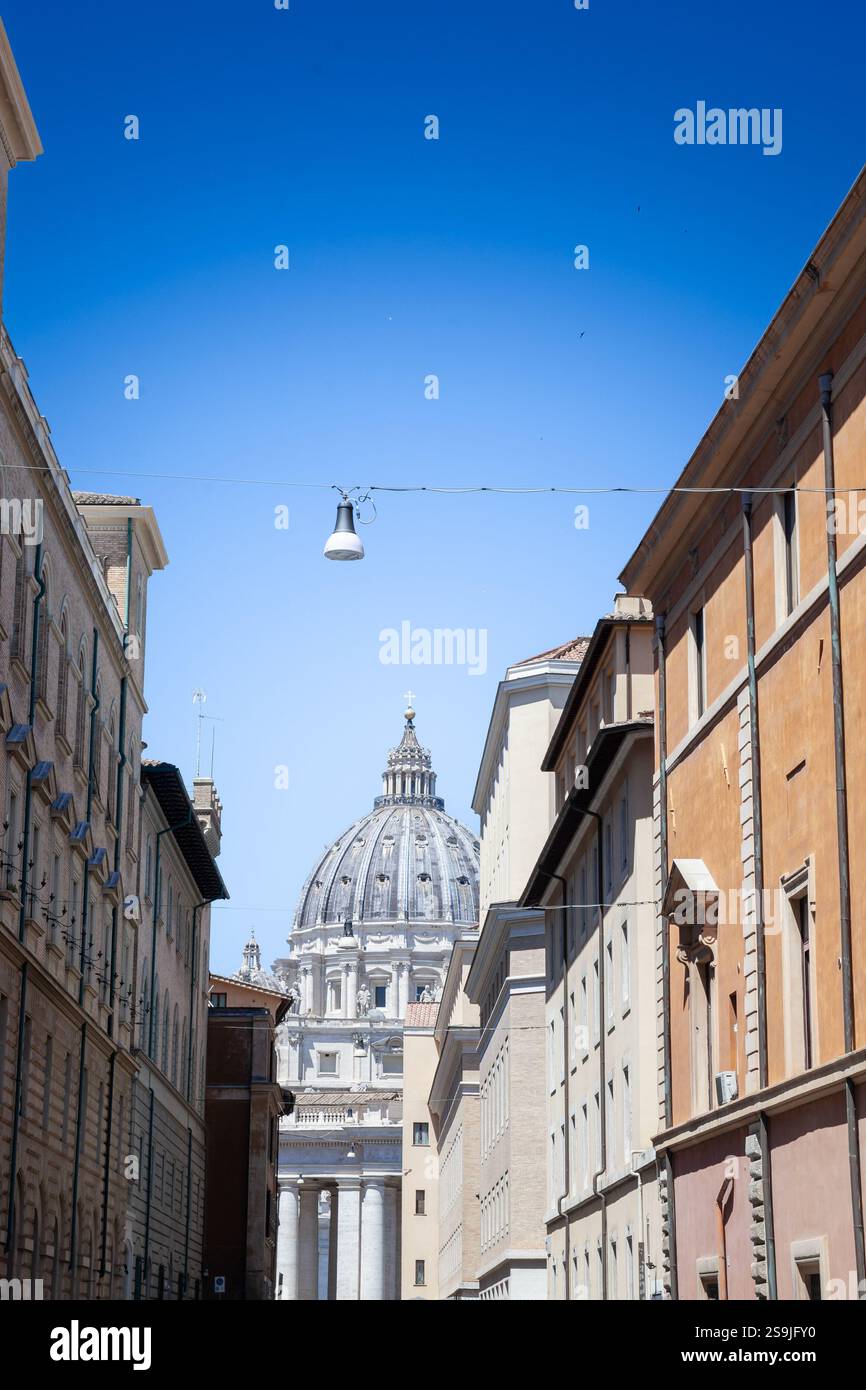 Saint Peter’s Basilica dome peeks between narrow Roman buildings ...
