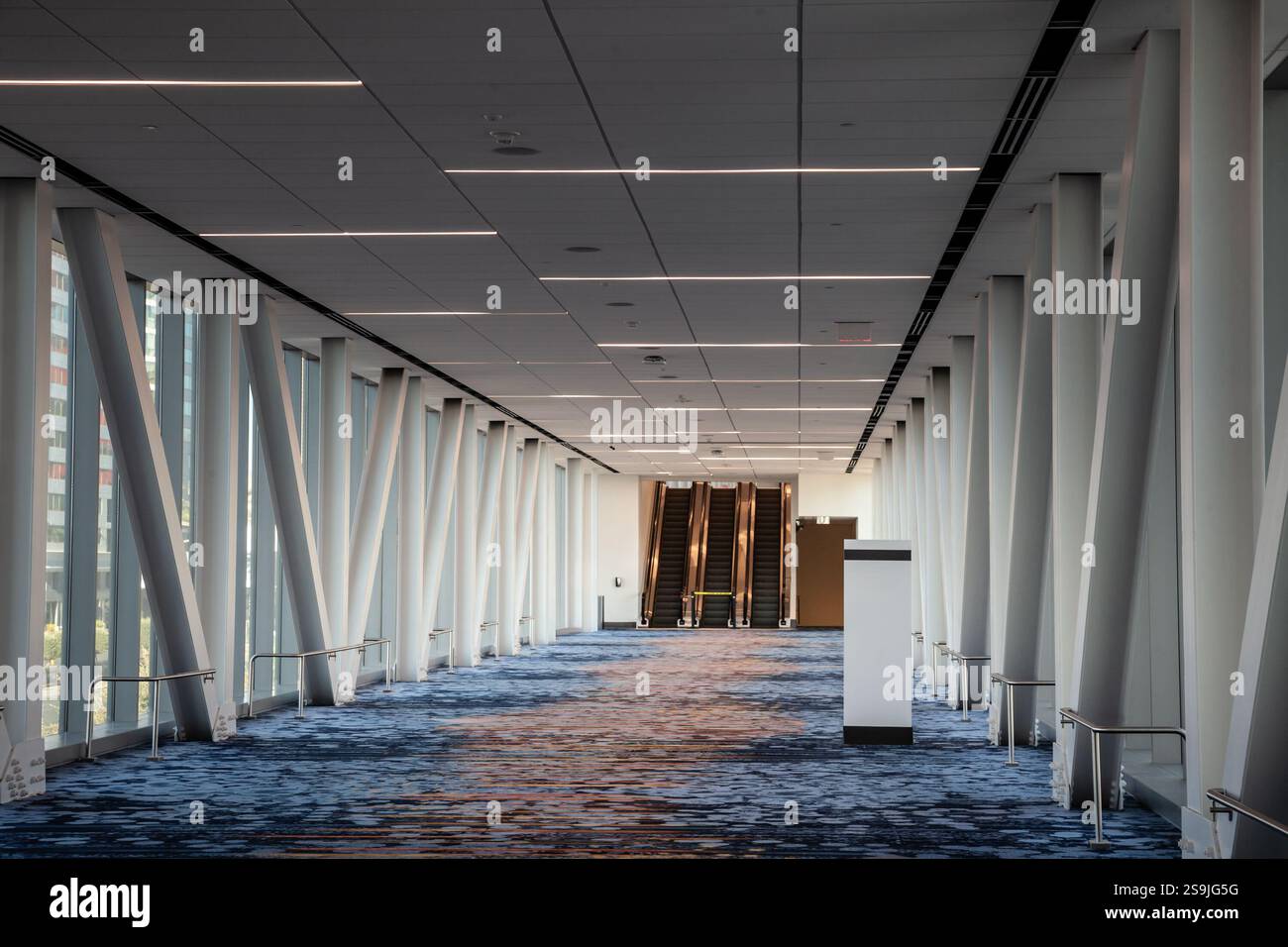 A bright, modern hallway features floor-to-ceiling windows and angled ...