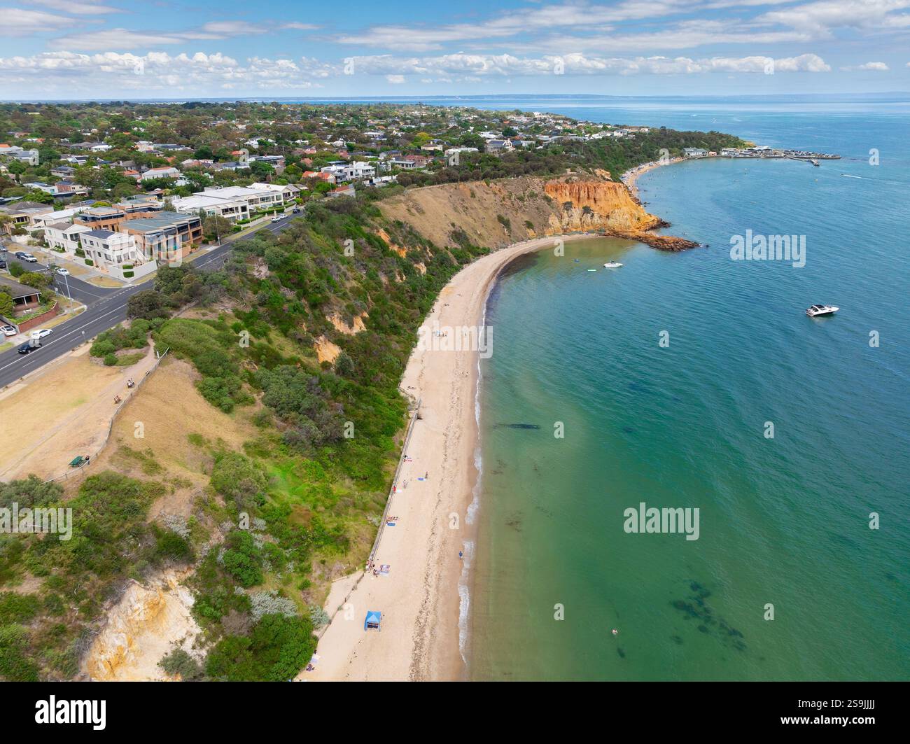 Aerial view of a narrow sandy beach below vegetated cliffs and a ...
