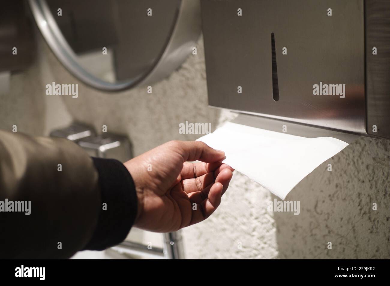 Hand reaching for paper towel in a modern restroom setting during the ...