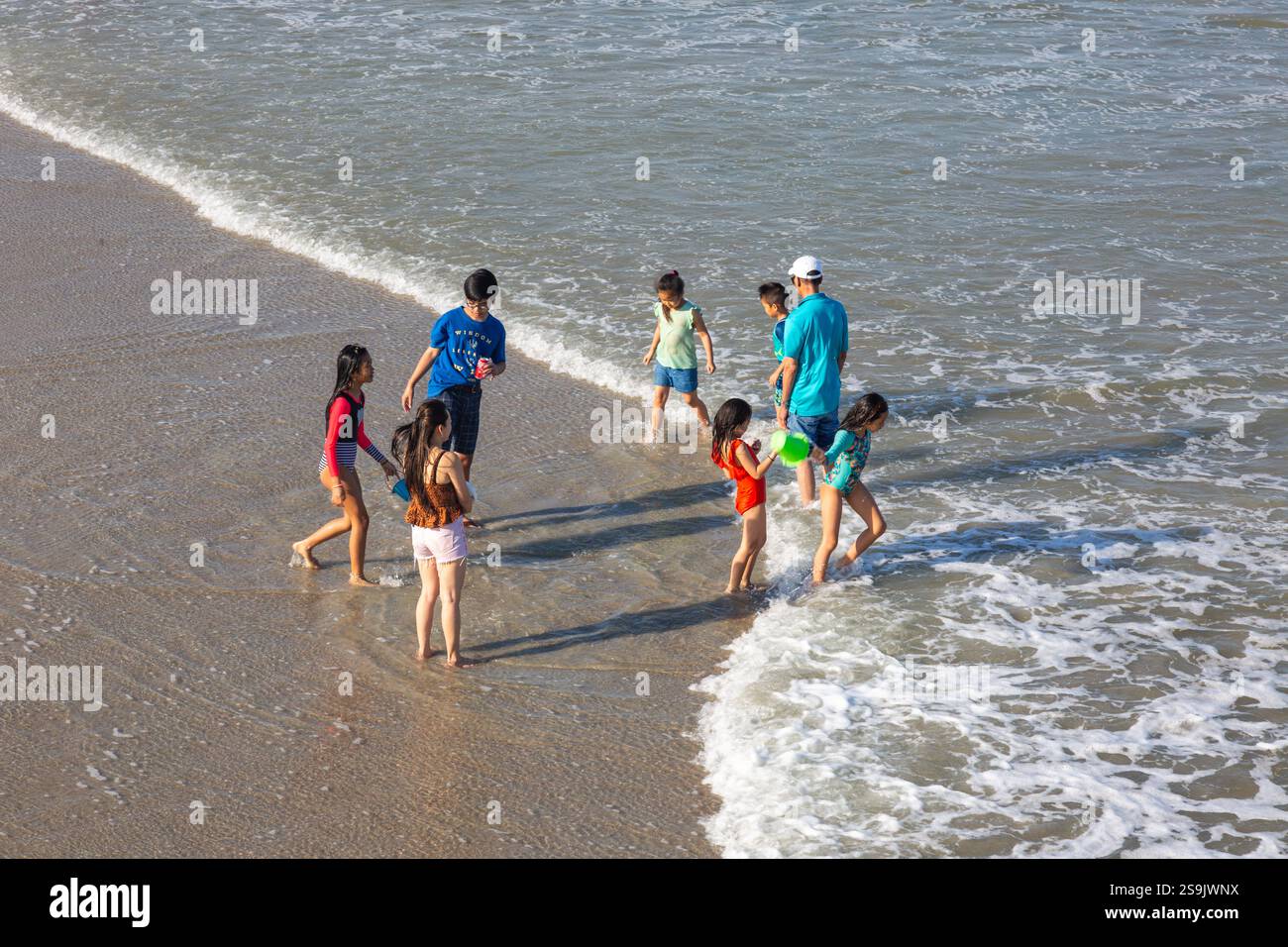 A family wades in the shallow water of the Atlantic Ocean at Myrtle Beach, South Carolina, USA ...