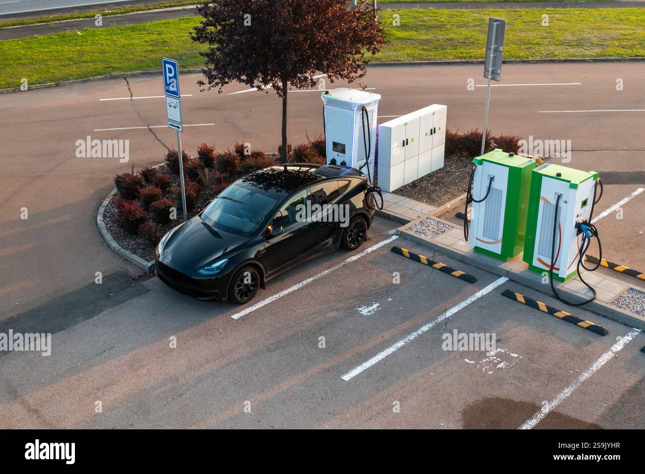 Black electric vehicle is receiving power at a public charging point ...