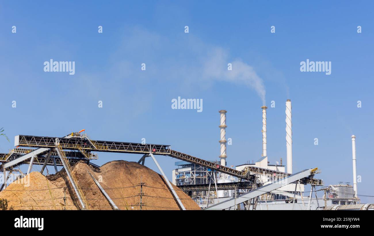 Biomass power plant with wood fuel storage system amidst blue sky ...