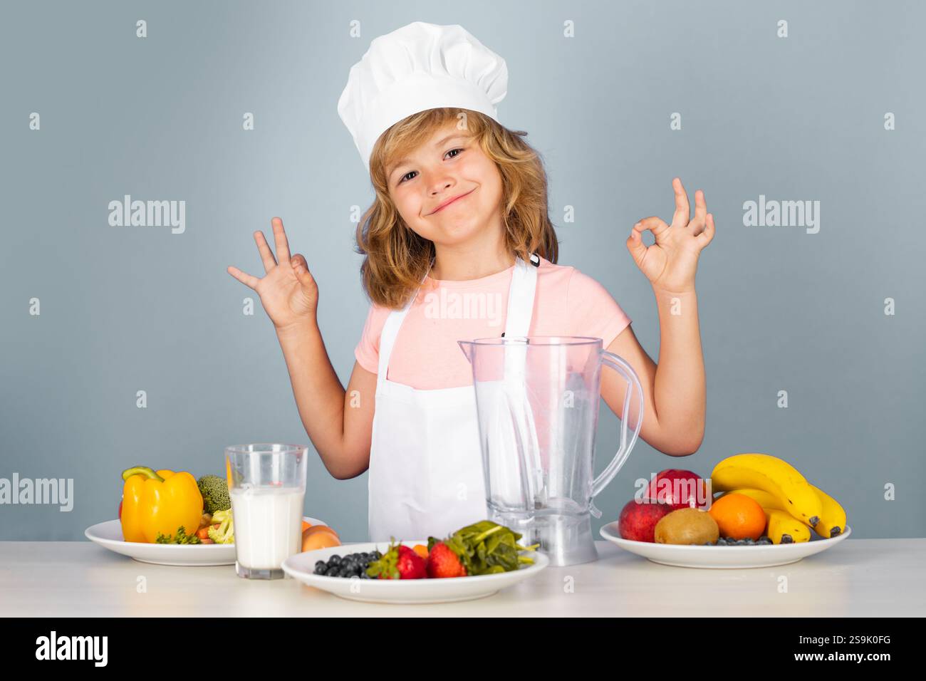 Child chef cook prepares food on isolated grey studio background. Kids ...