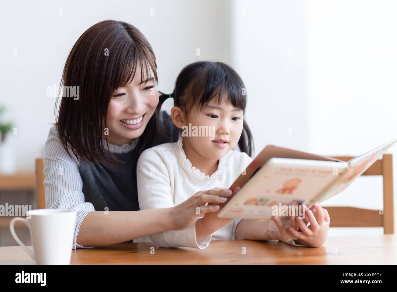 Parent and child reading a picture book Stock Photo - Alamy