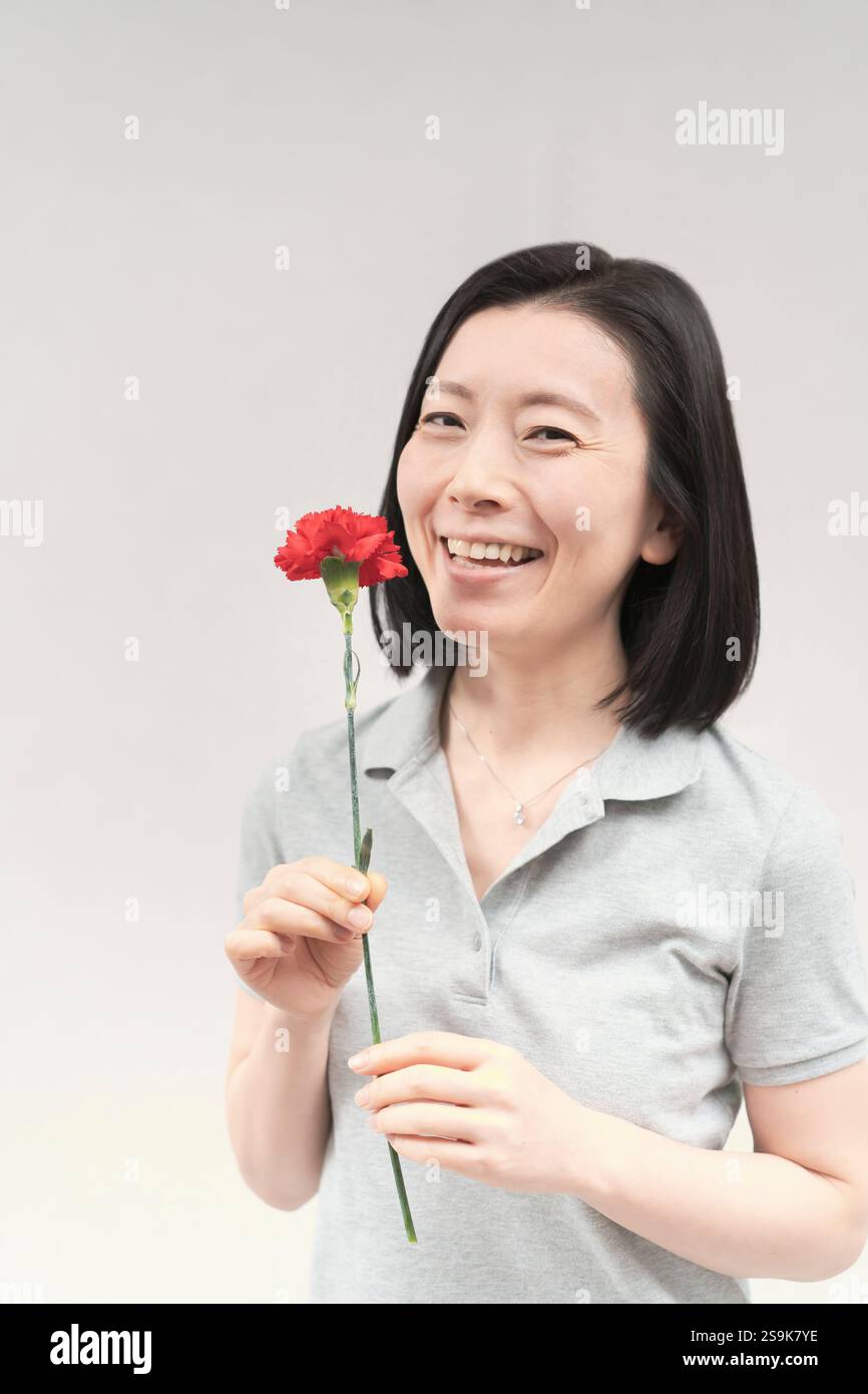Smiling woman holding carnation Stock Photo - Alamy