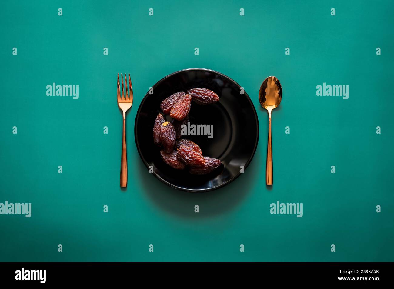 Date fruits set as moon symbol on black plate with golden fork and ...