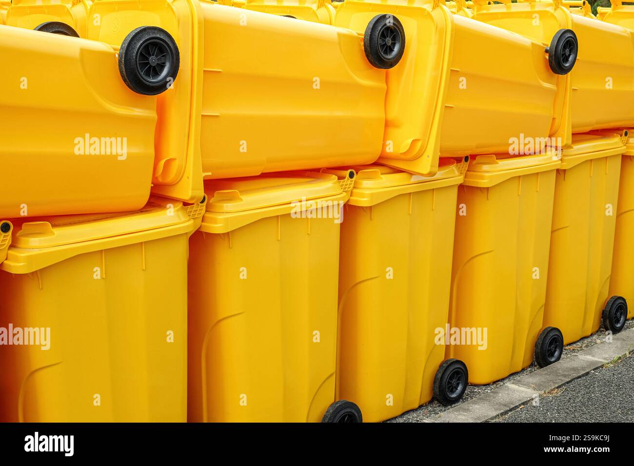 rows of new municipal colored trash cans with wheels, ready to be ...
