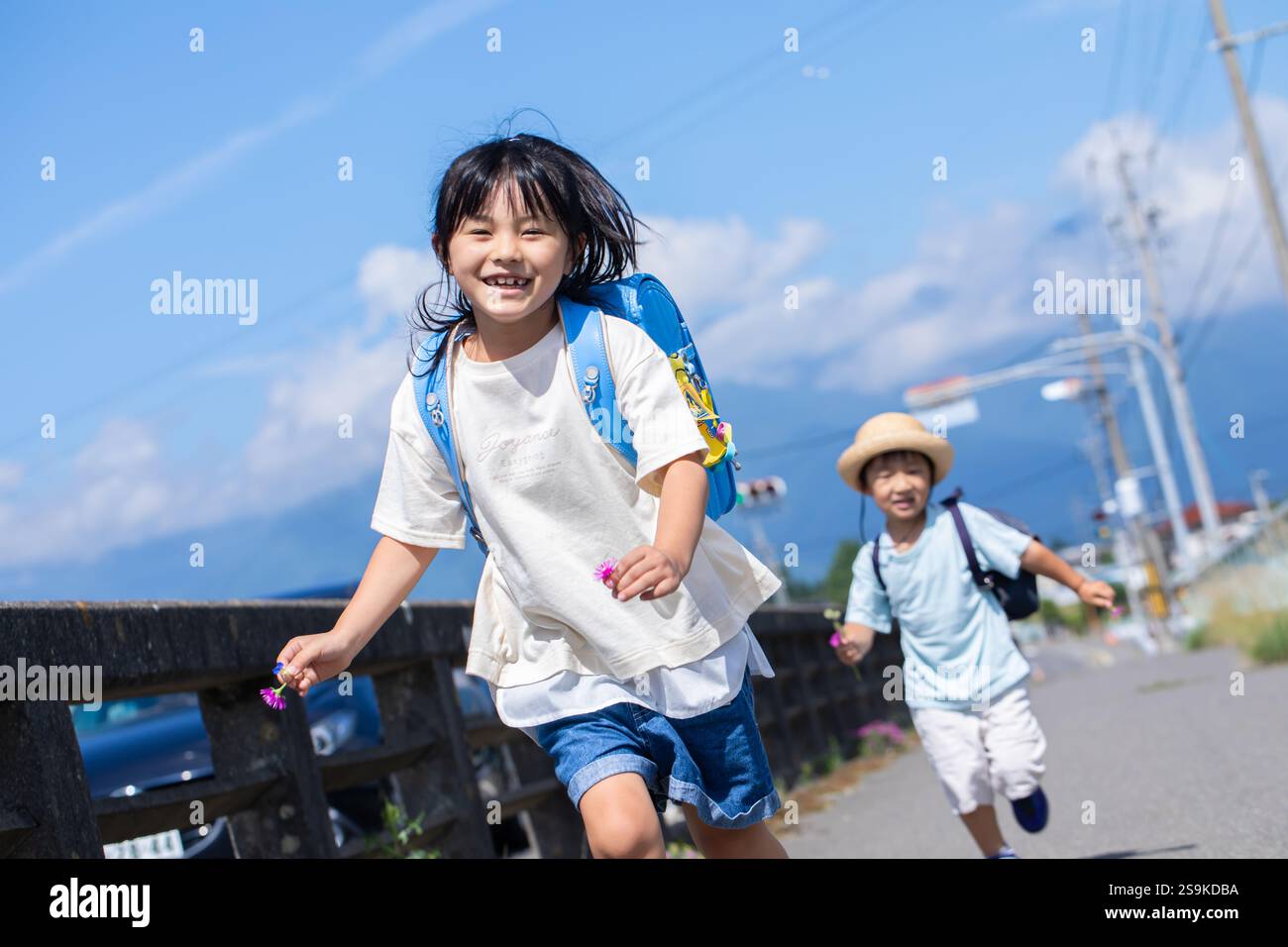 Primary school girl and kindergarten boy running along the road Stock ...