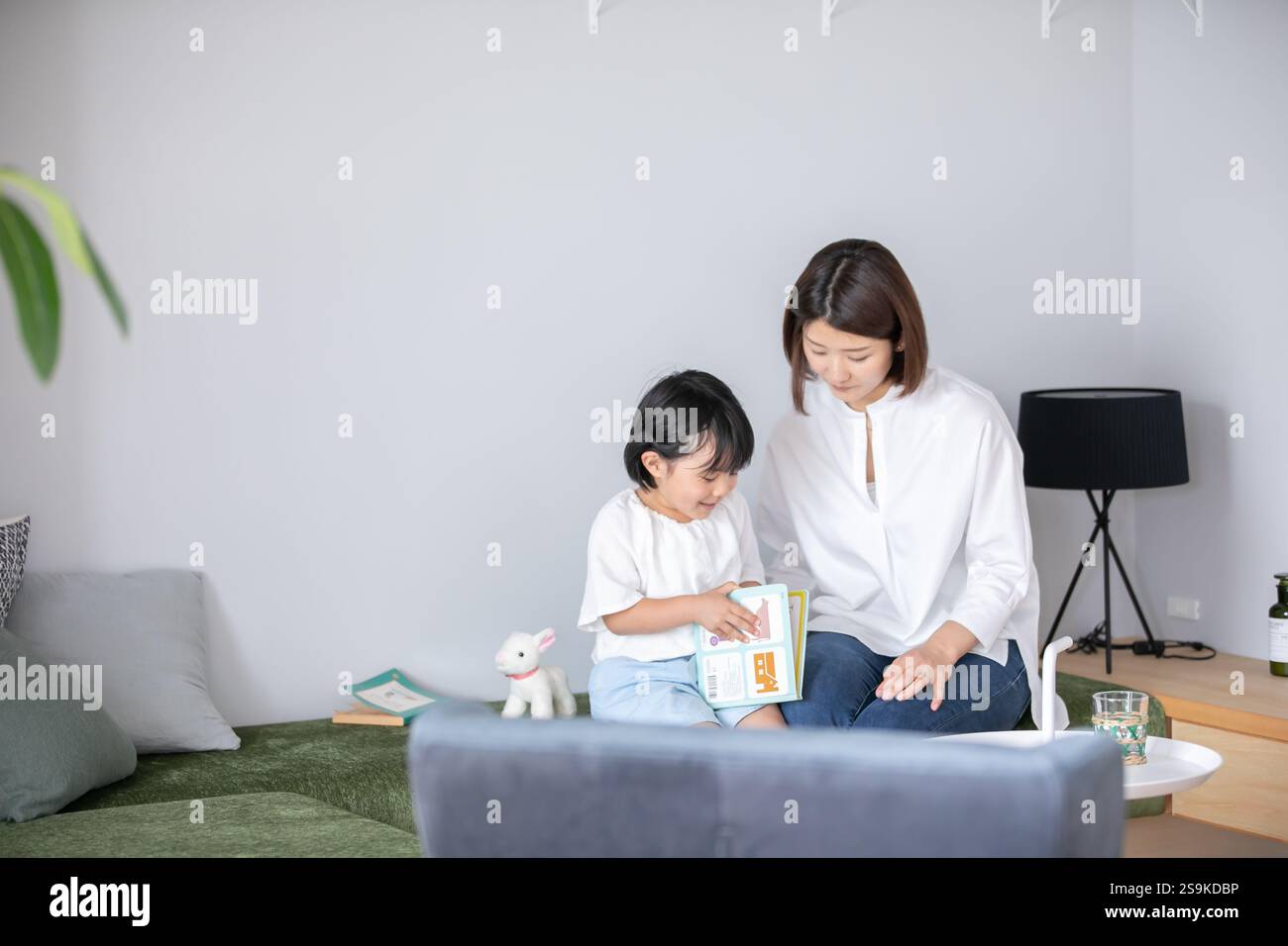 Parent and child reading a book Stock Photo - Alamy