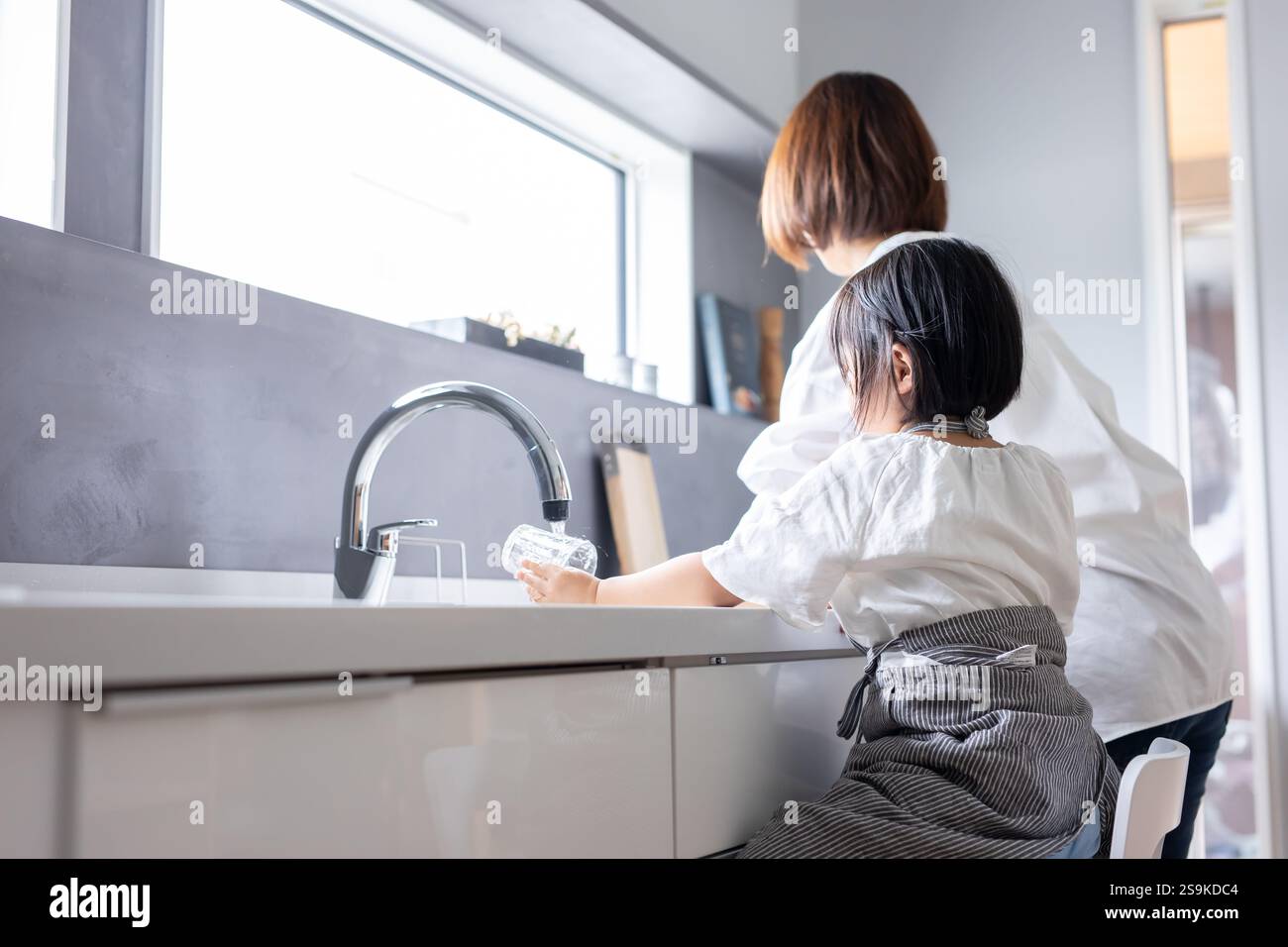 Girl helping with the washing-up Stock Photo - Alamy