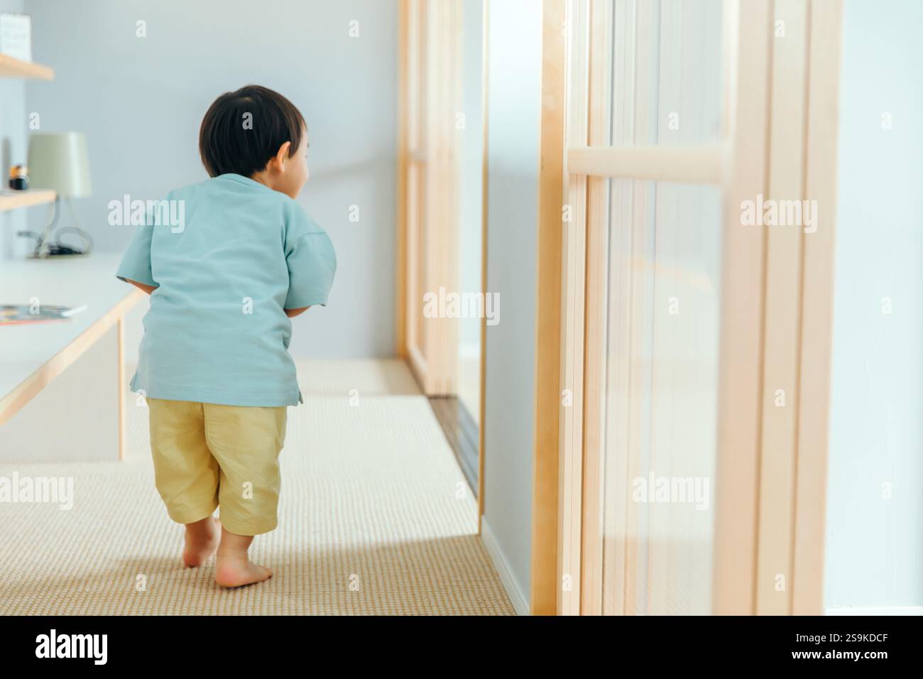 Three-year-old boy sneaking a peek into room Stock Photo - Alamy