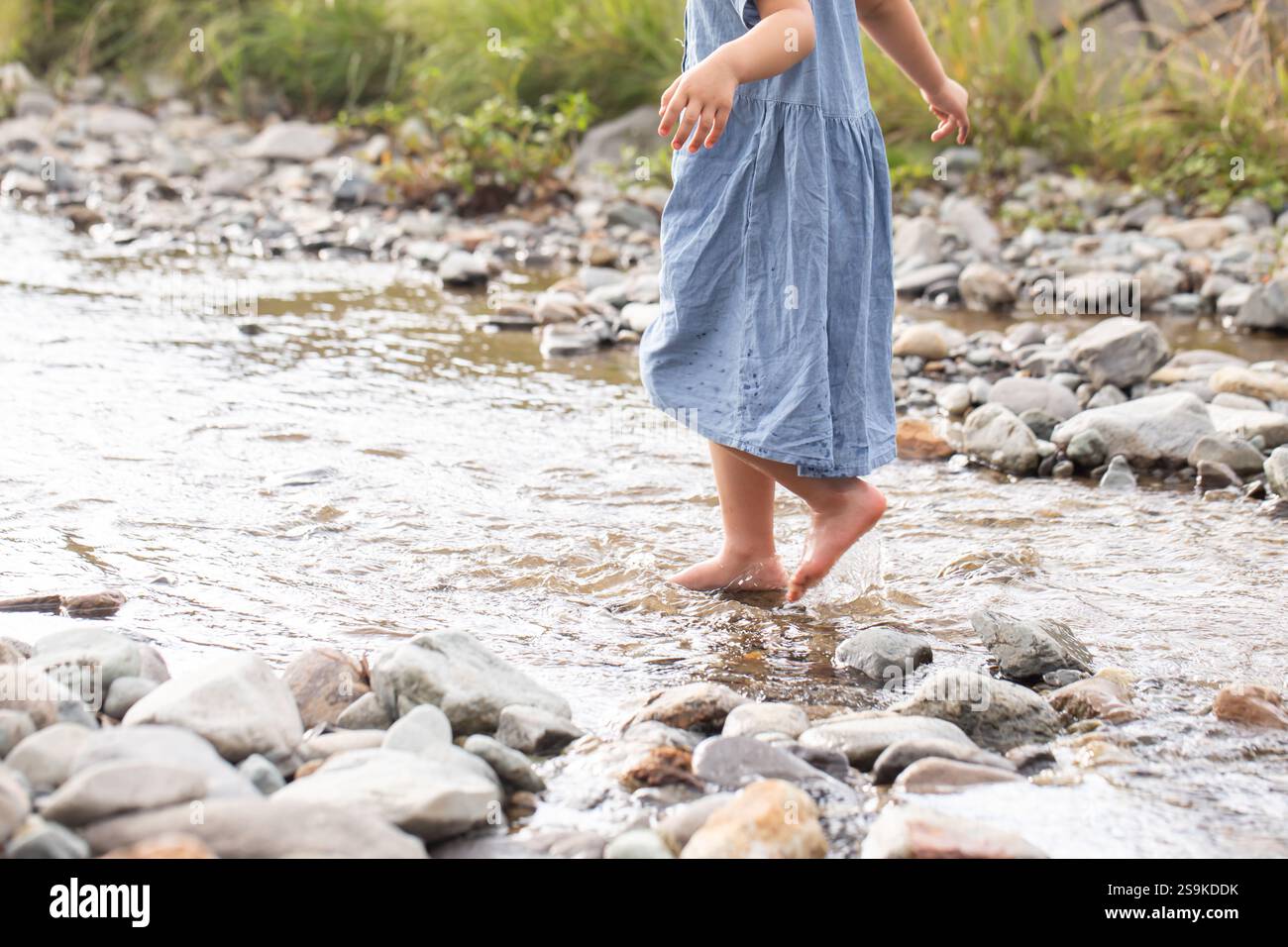 Girl's feet playing in the water in the river Stock Photo - Alamy