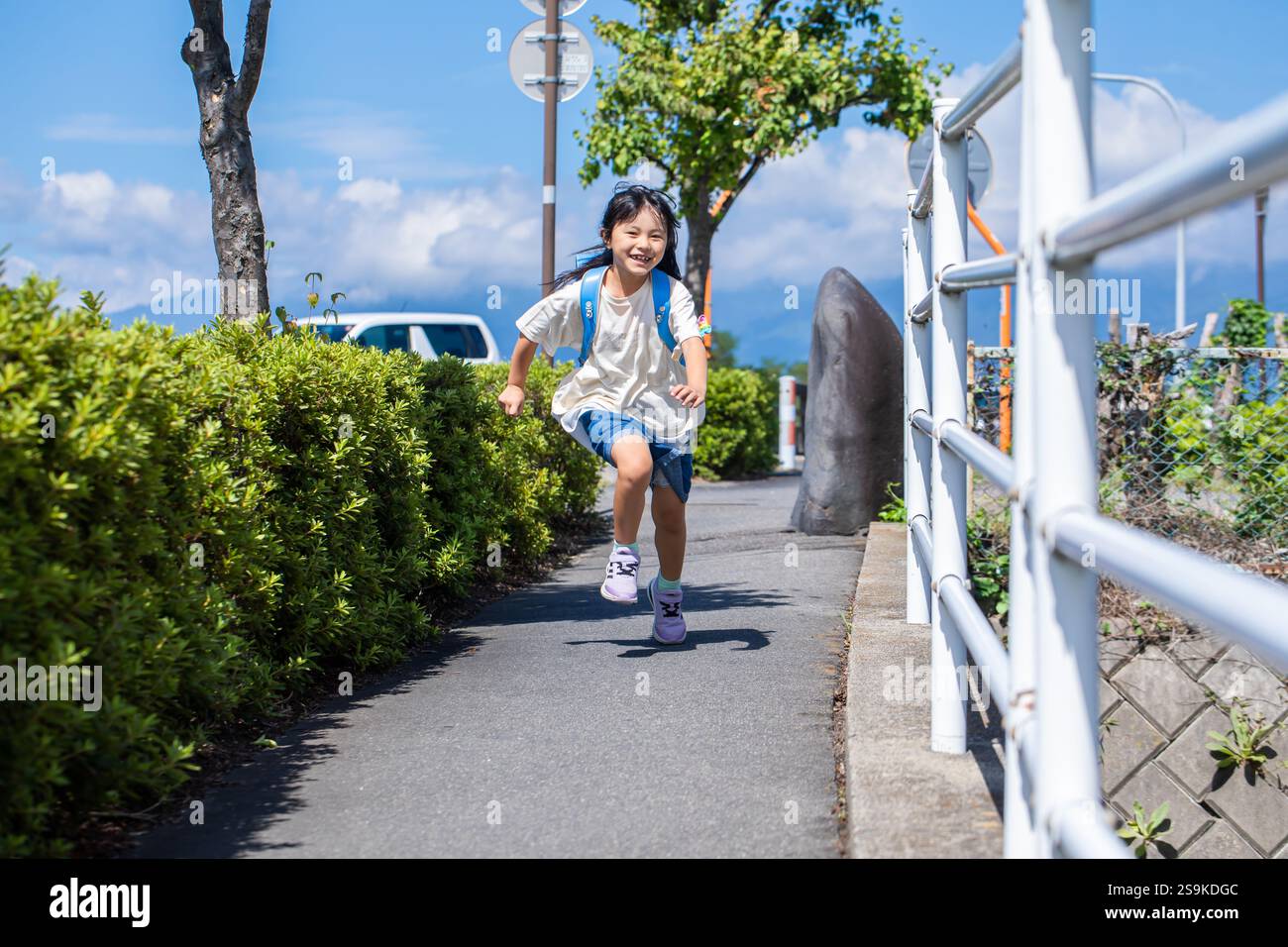 Primary school girl running along the road Stock Photo - Alamy