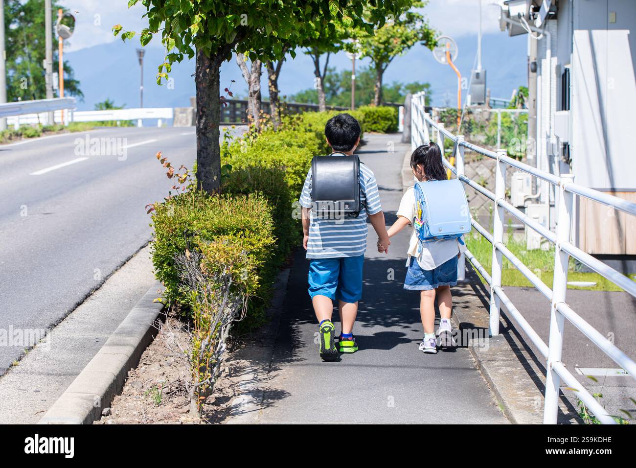 Siblings of primary school children walking on the sidewalk holding ...