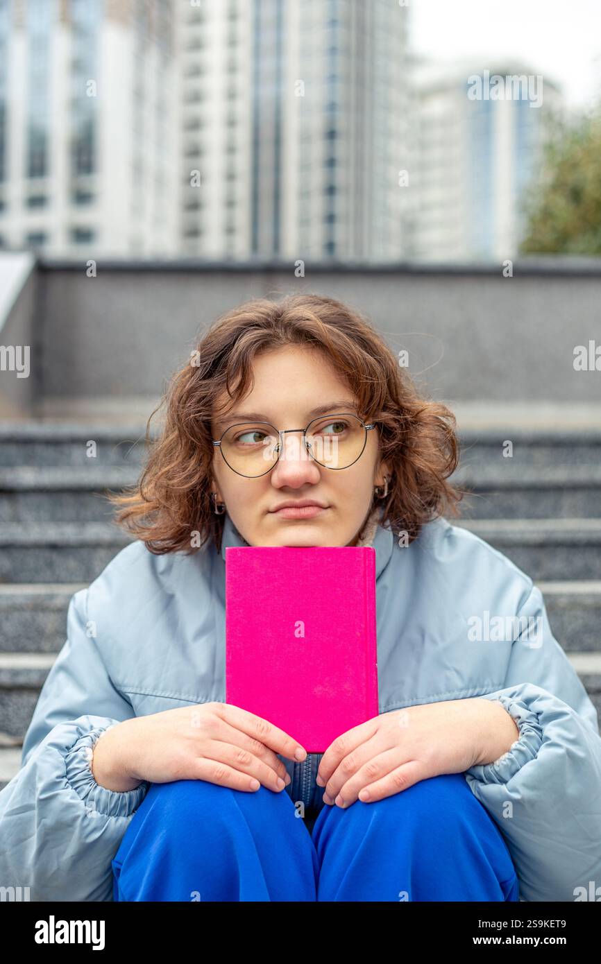 Sad girl student with a book. Teenage girl in the city. Learning ...