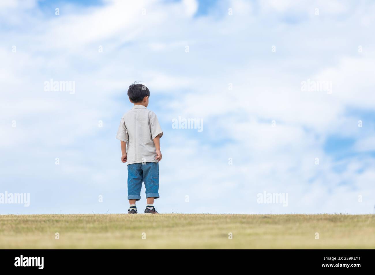 Boy standing back on hill Stock Photo - Alamy