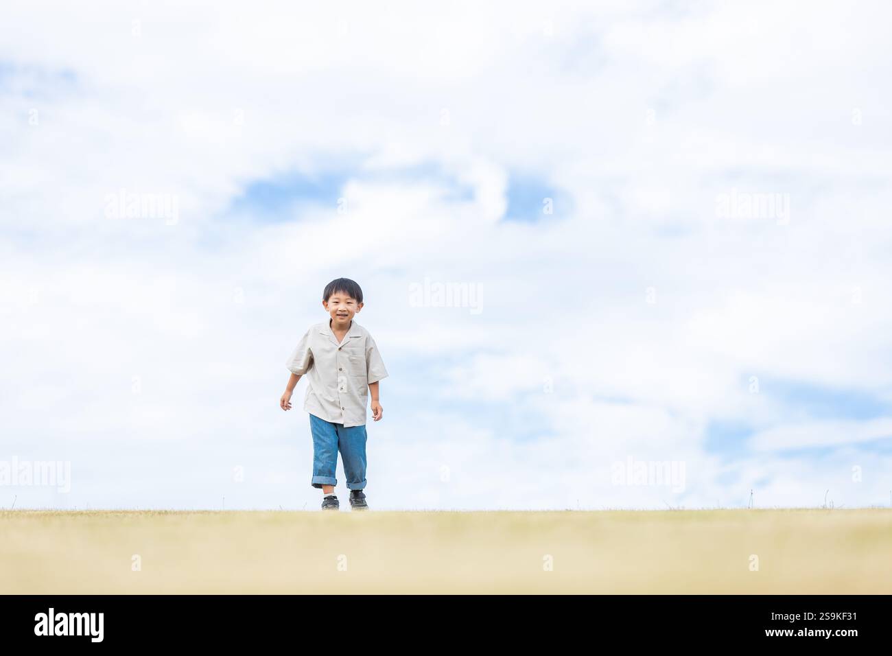 Boy walking on grassland Stock Photo - Alamy