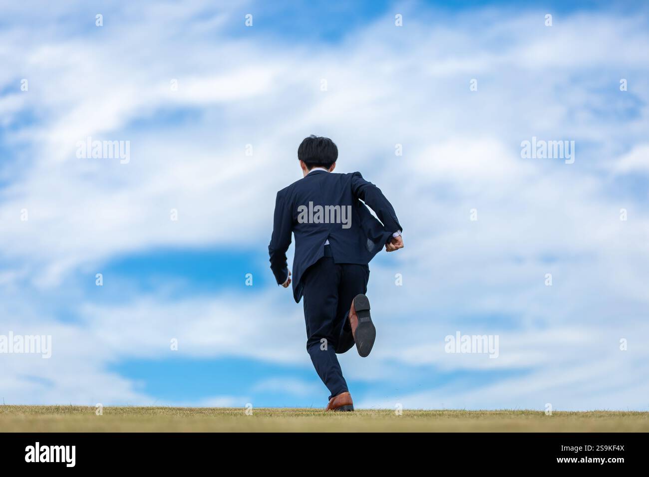 Man in suit running across open meadow Stock Photo - Alamy