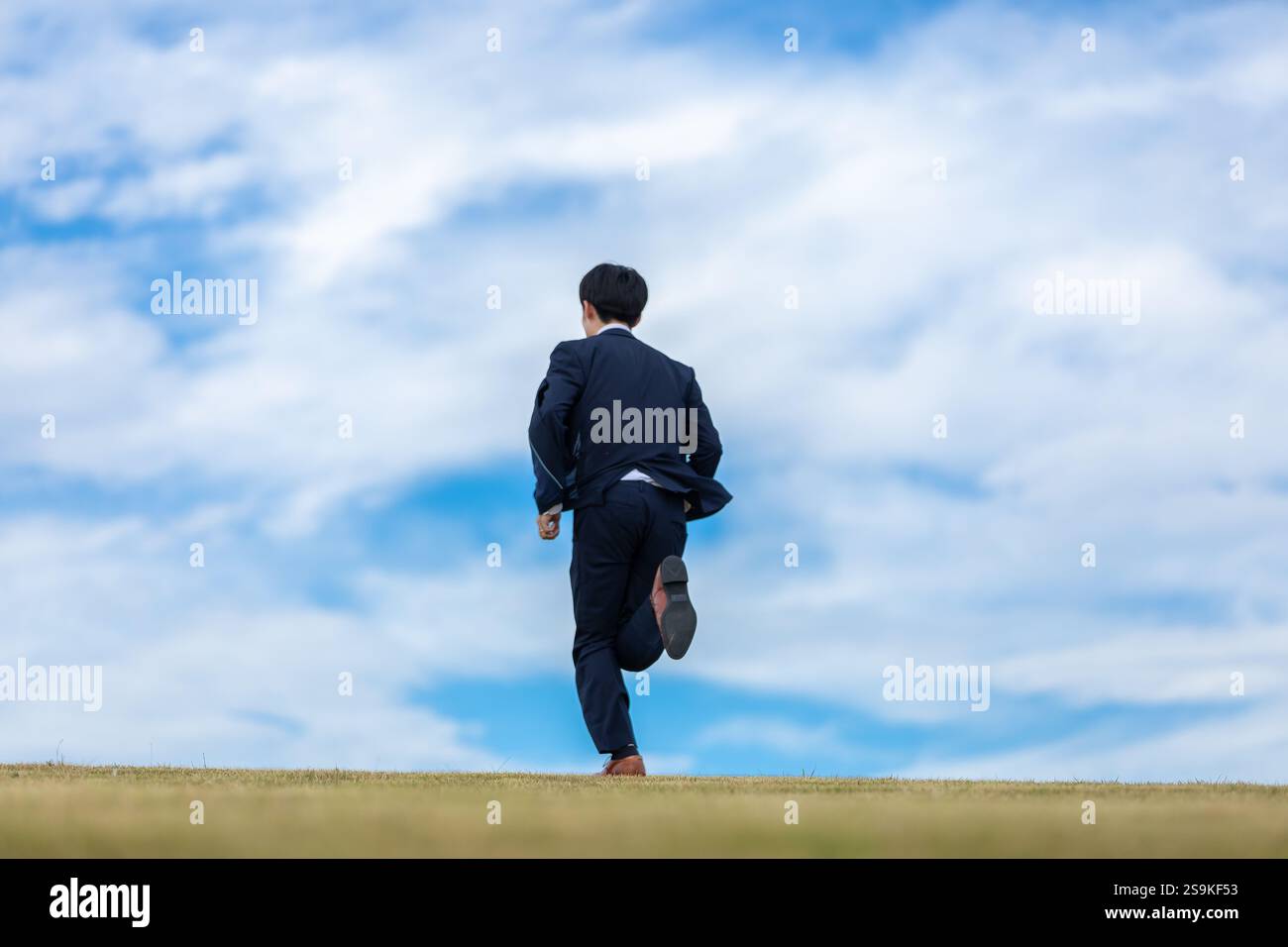 Man in suit running across open meadow Stock Photo - Alamy