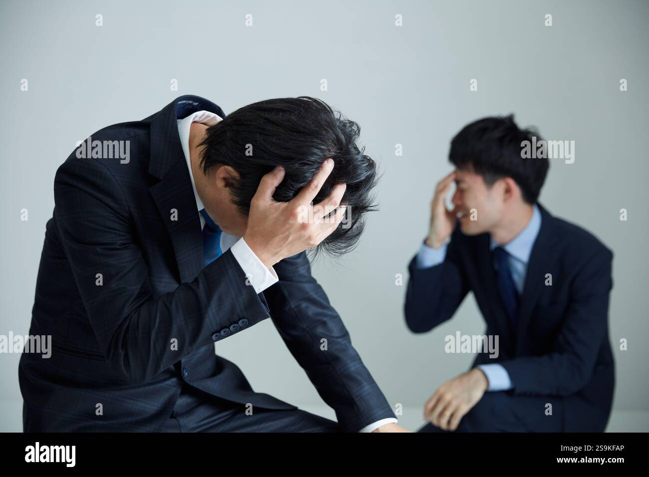 Businessman with head held in distress Stock Photo - Alamy
