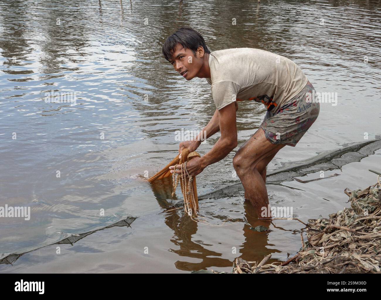 A half-Khmer, half-Vietnamese male fisherman is casting net fishing in ...