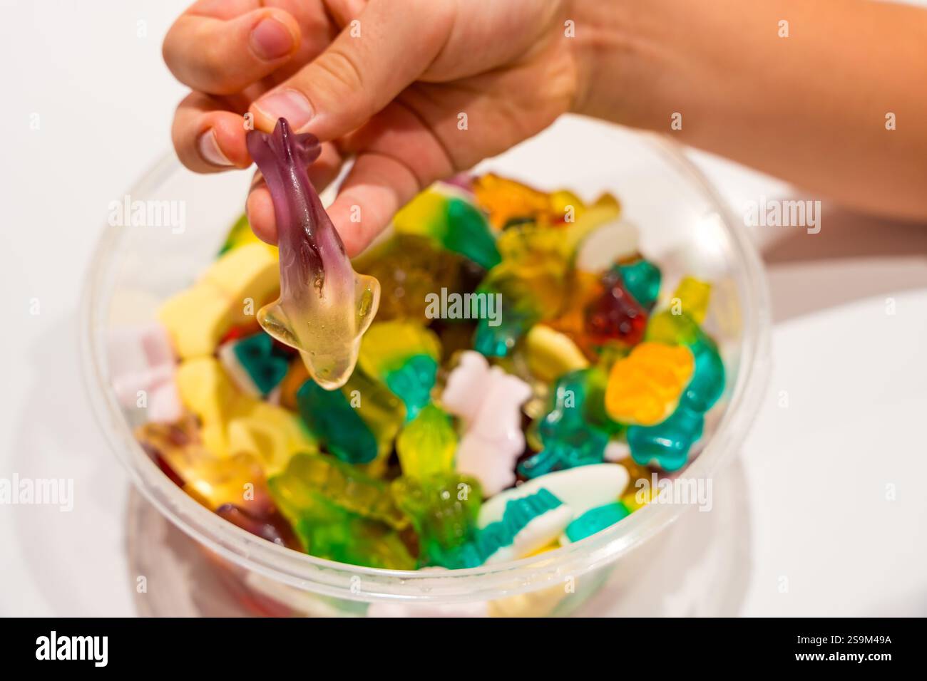 A close-up of a childs hand picking a gummy Swedish candies shaped like ...