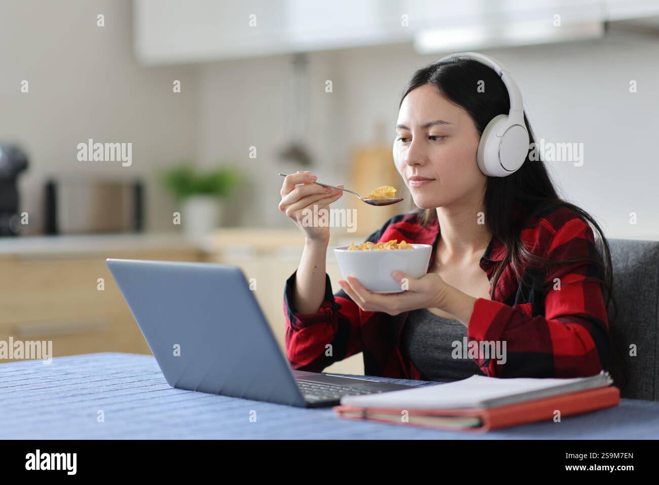 Asian student learning and eating cereals in the kitchen at home Stock ...