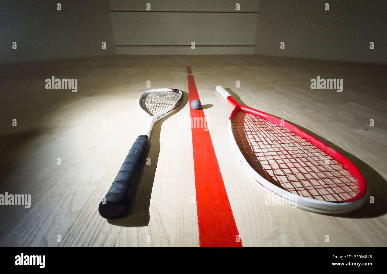 Two rackets and two squash balls lie on the parquet floor. High quality ...