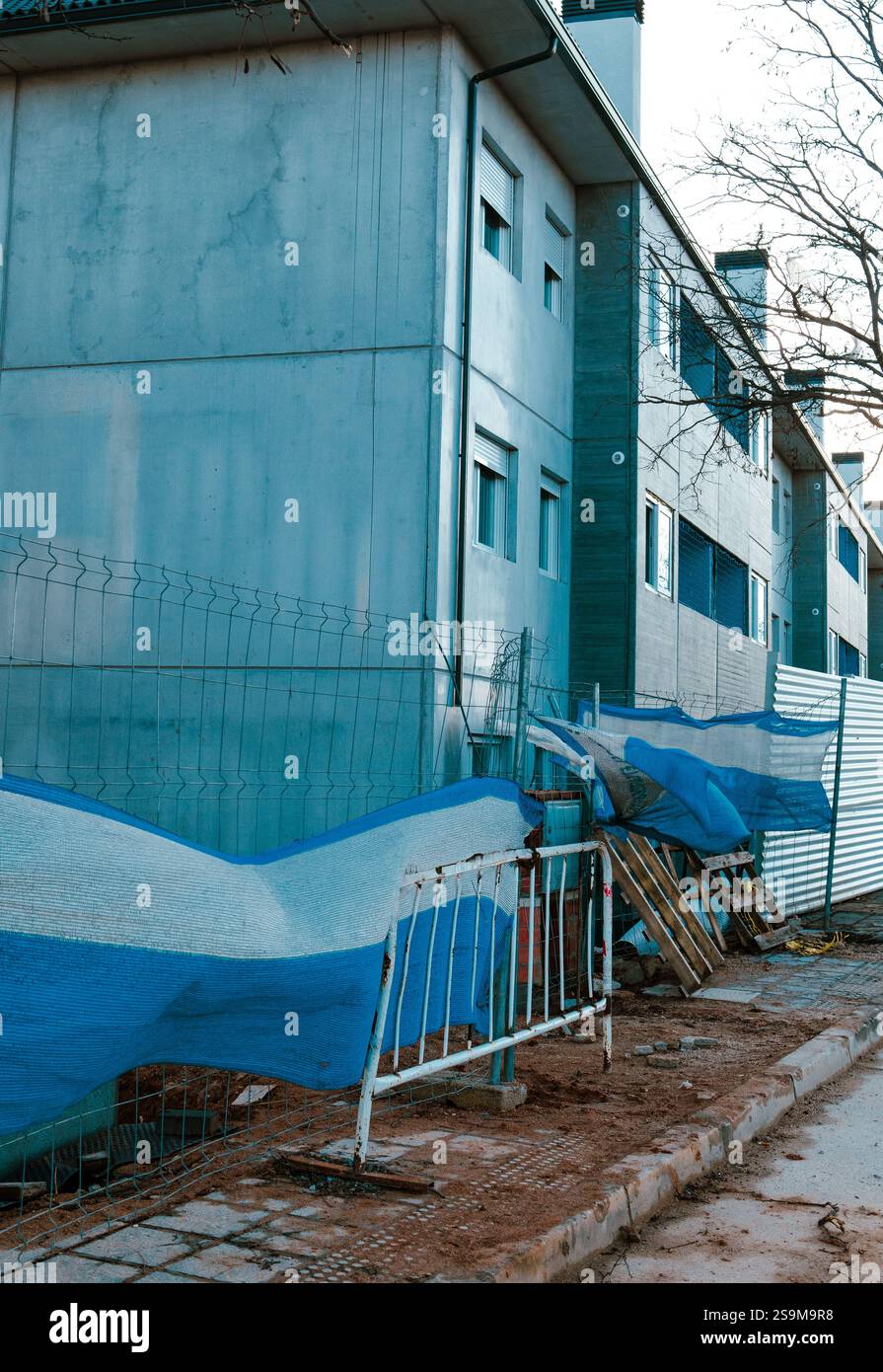 A blue tarp is covering a fence. The fence is next to a building Stock ...