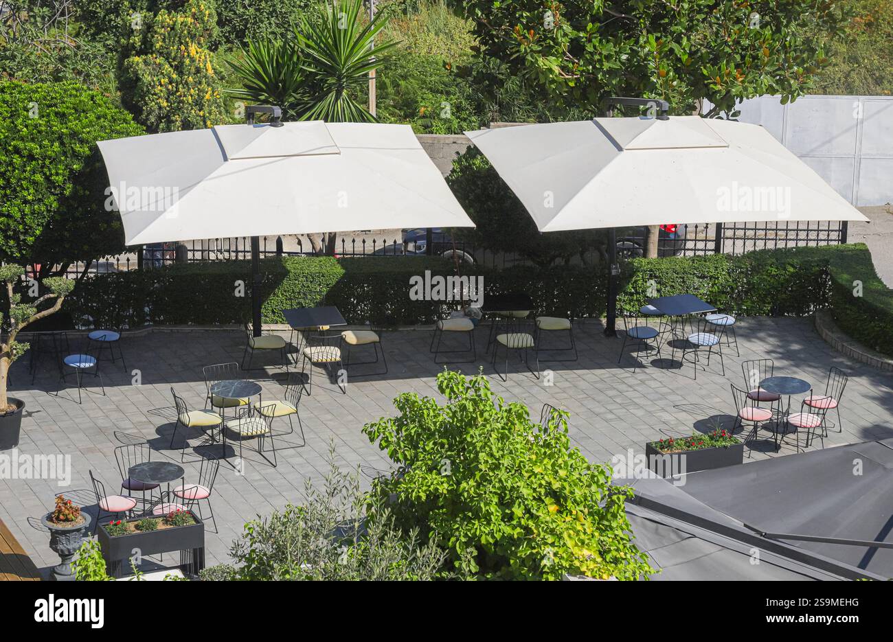 Shaded tables and chairs are arranged in a peaceful outdoor dining area ...